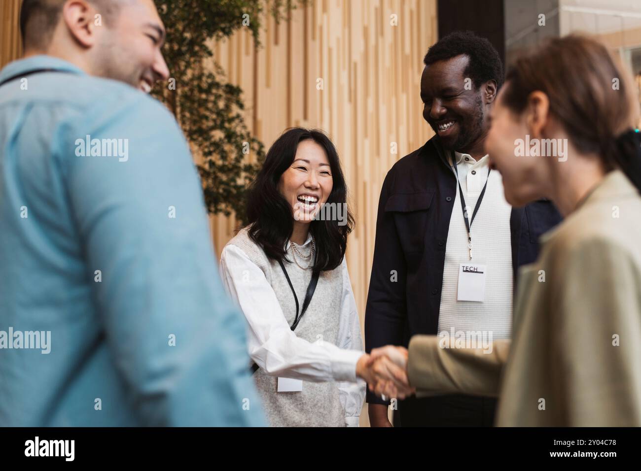 Happy female entrepreneur doing handshake with young delegate during ...
