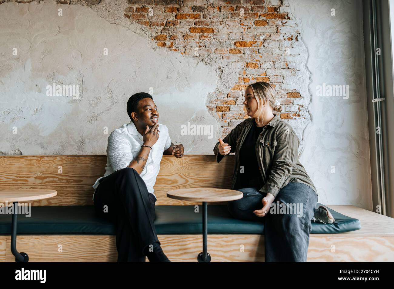 Female programmer talking with male colleague sitting on bench against ...