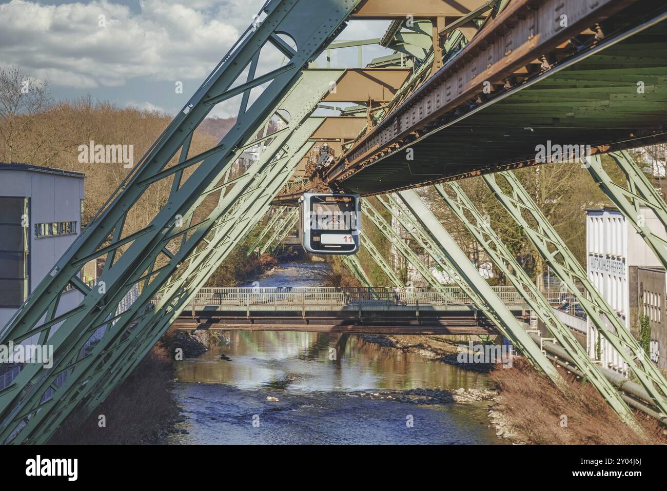 A suspension railway runs on an elevated bridge over a river, the scene ...