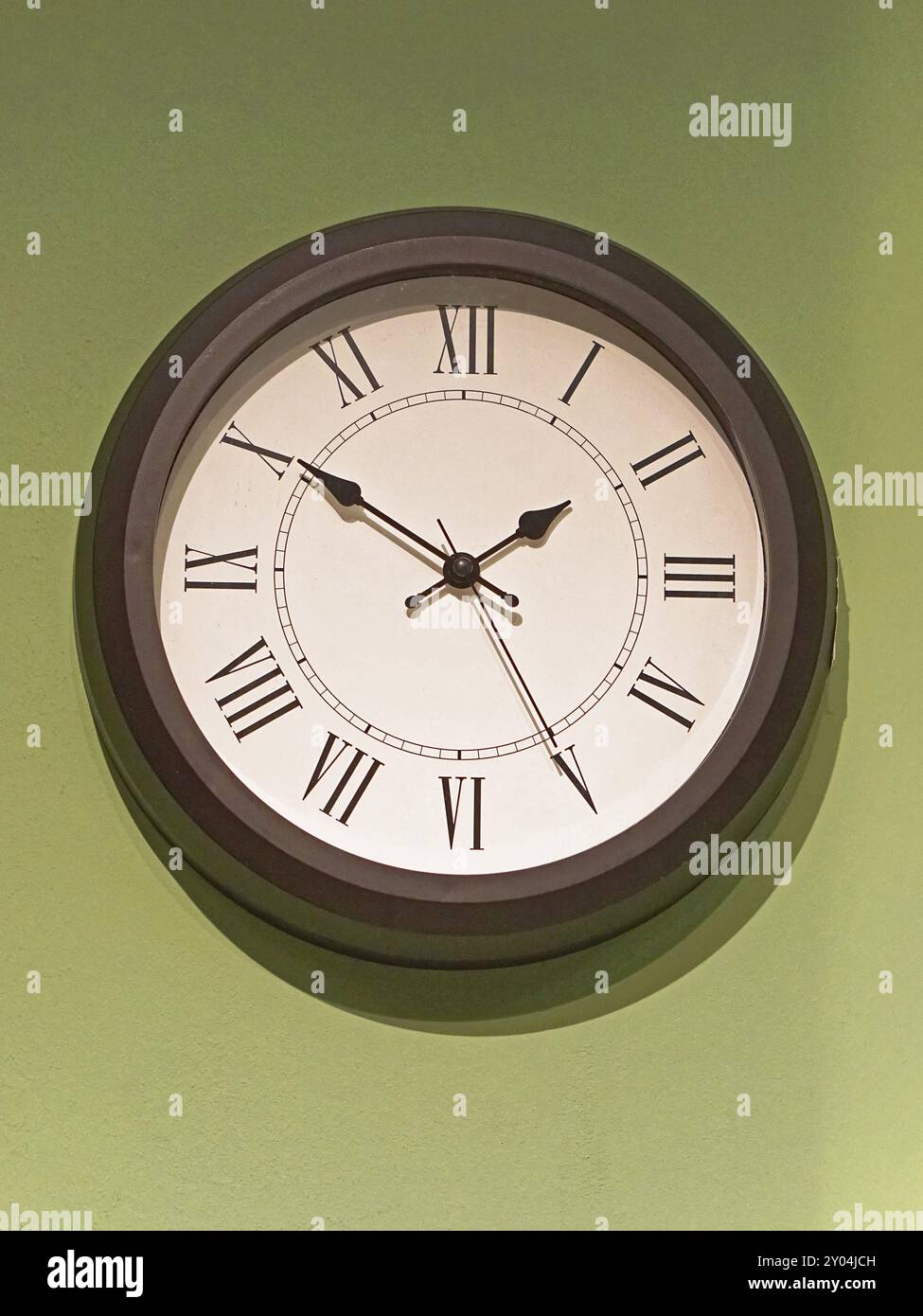 Big old clock with Roman numbers at green wall Stock Photo - Alamy