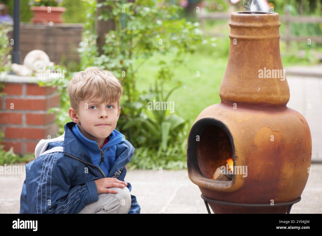 Cute blond boy sitting down on the ground with his satchel on his back ...