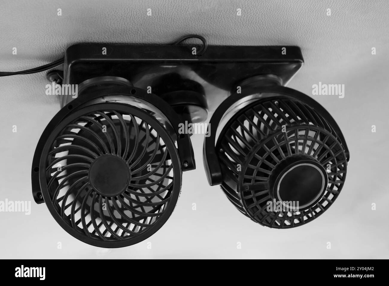 Portable fan on the ceiling in a car. Summer heat. Dual-head car ...