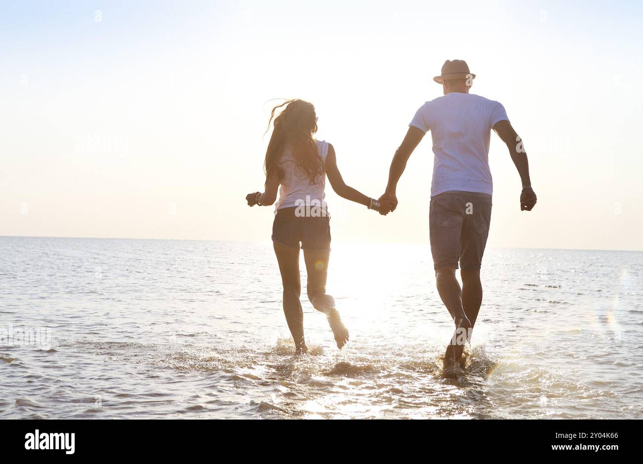 Happy young couple having fun running on beach at sunset. Traveling ...