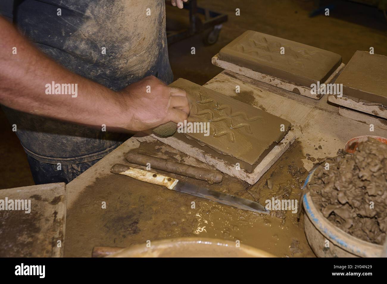 Detailed view of a worker moulding a pattern in a clay brick ...