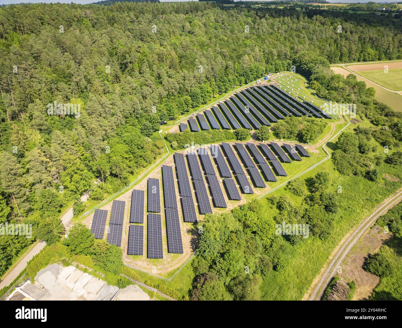 Overview of a solar panel landscape surrounded by lush forests and open ...