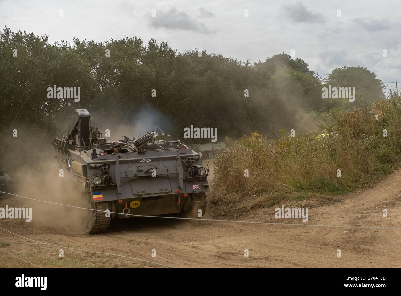 Military tank and off road armoured vehicle driving around a dirt track ...