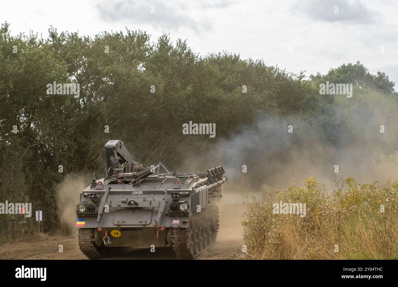 Military tank and off road armoured vehicle driving around a dirt track ...