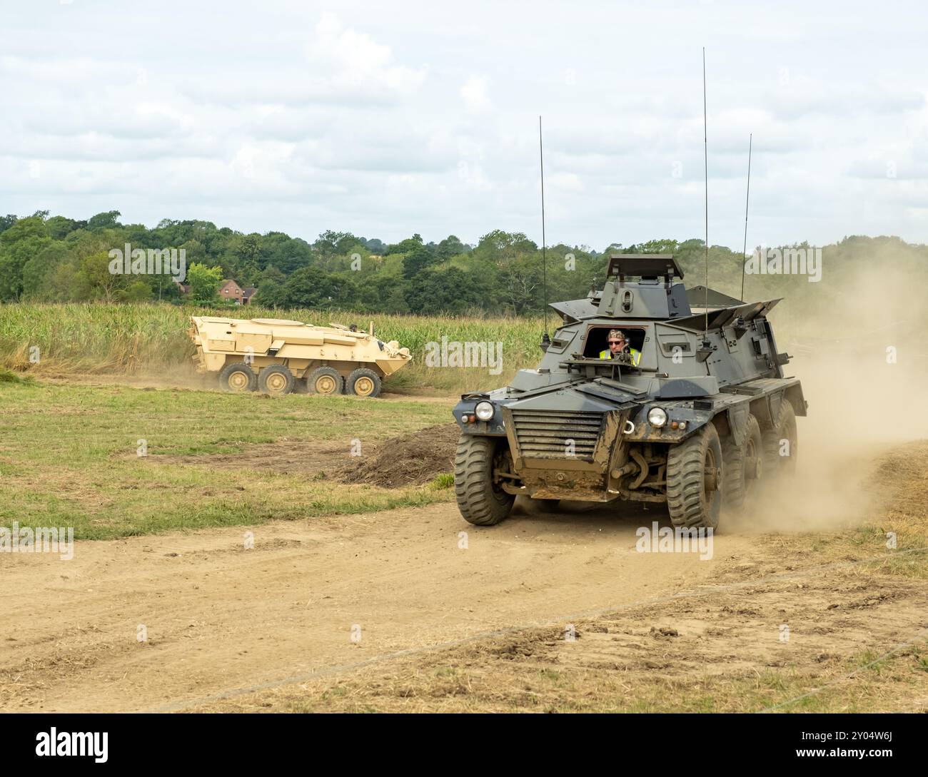 Military tank and off road armoured vehicle driving around a dirt track ...