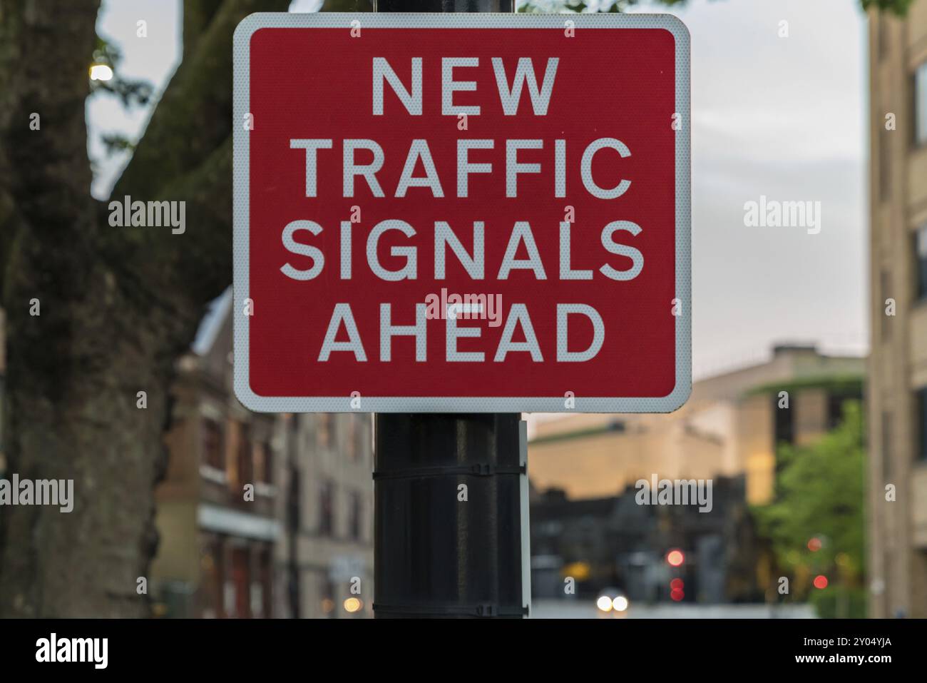 Sign: New traffic signals ahead, with some blurry traffic signals in ...