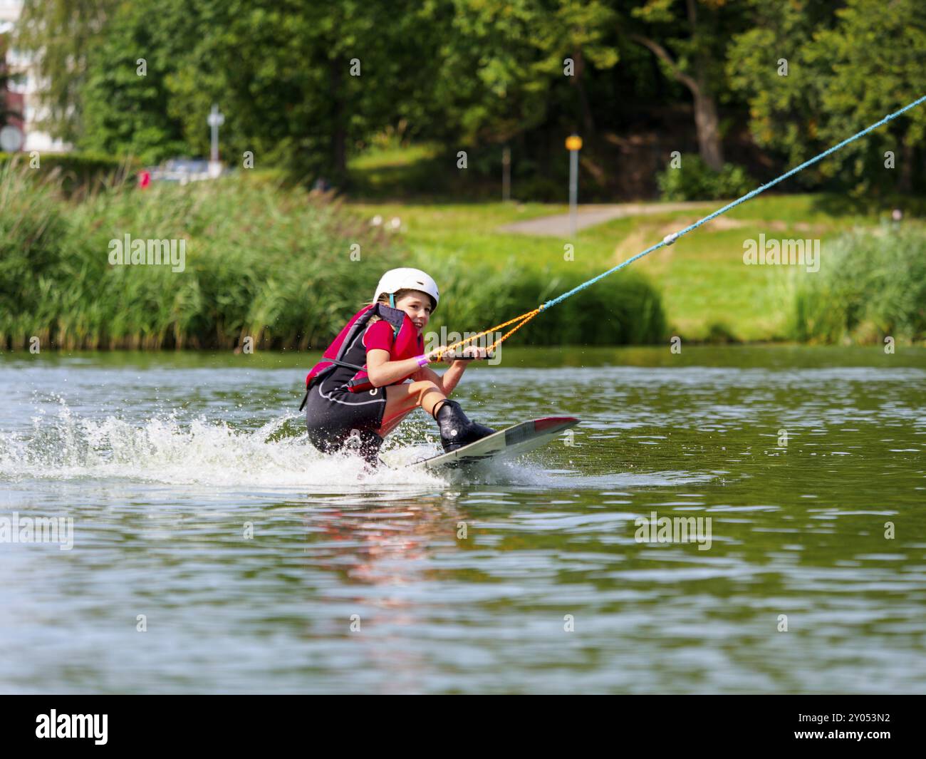 Boy or girl, water sports with wakeboard, red life jacket, water skiing ...