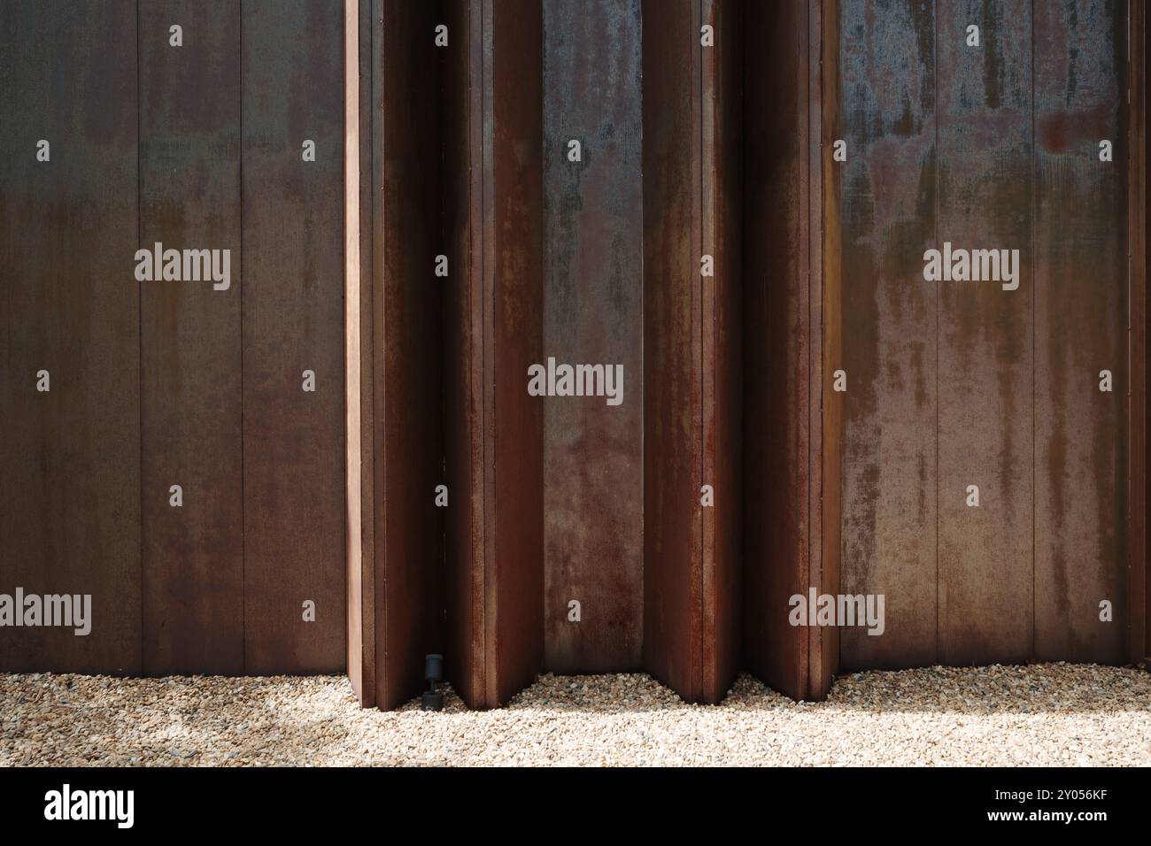 A close-up of an industrial rusted metal wall with large vertical beams ...