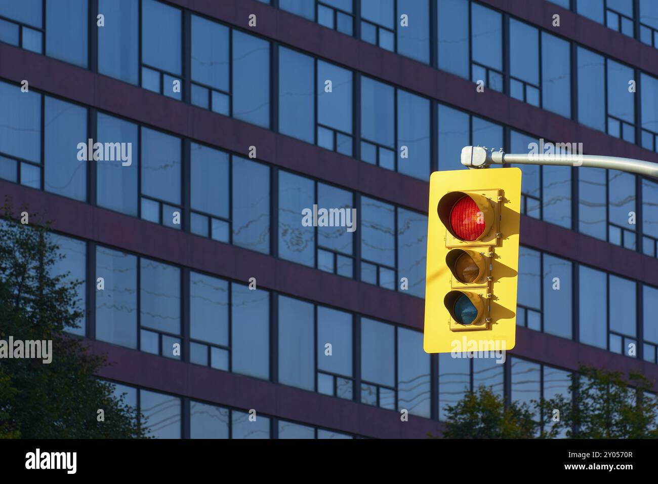A traffic light system with the red light shining in front of a modern ...