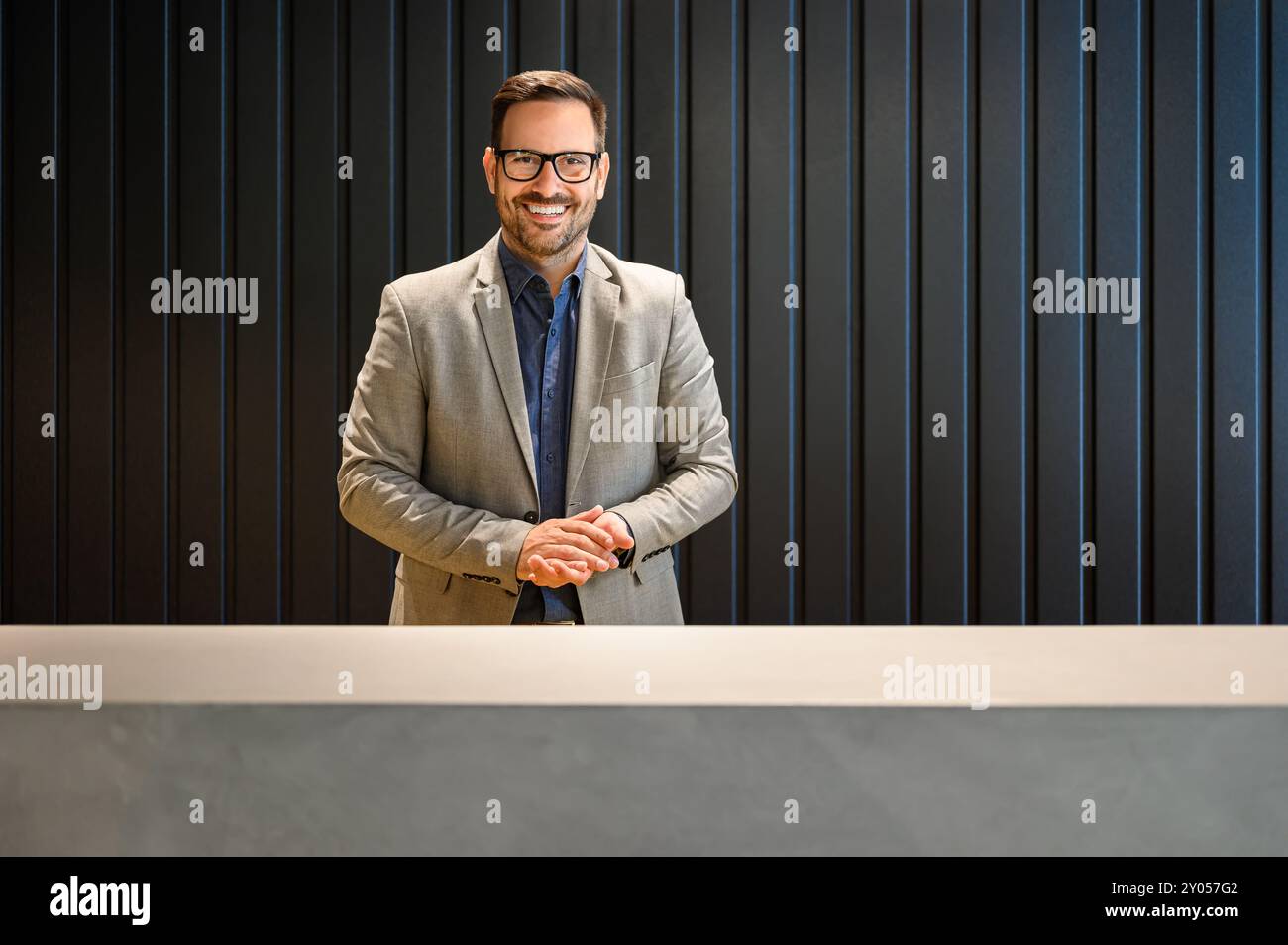 Portrait of confident male receptionist in eyeglasses looking at camera ...