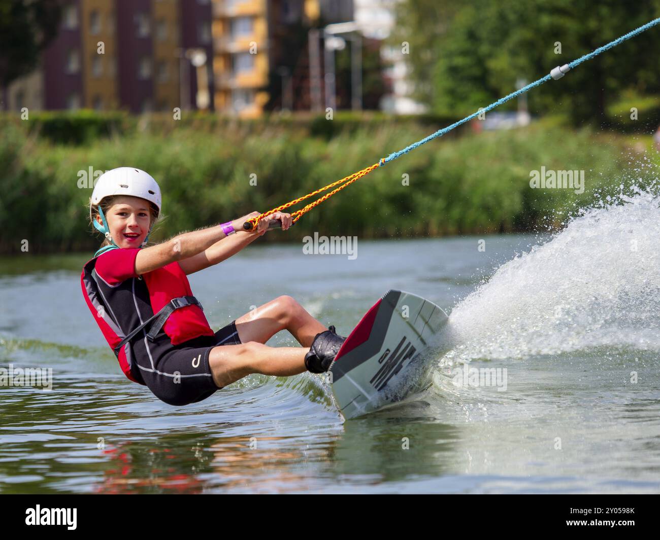 Boy or girl, water sports with wakeboard, red life jacket, water skiing ...