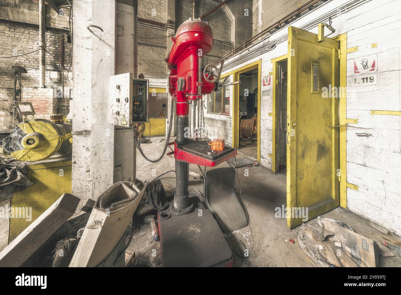 Abandoned workshop with a large red drilling machine and yellow doors ...