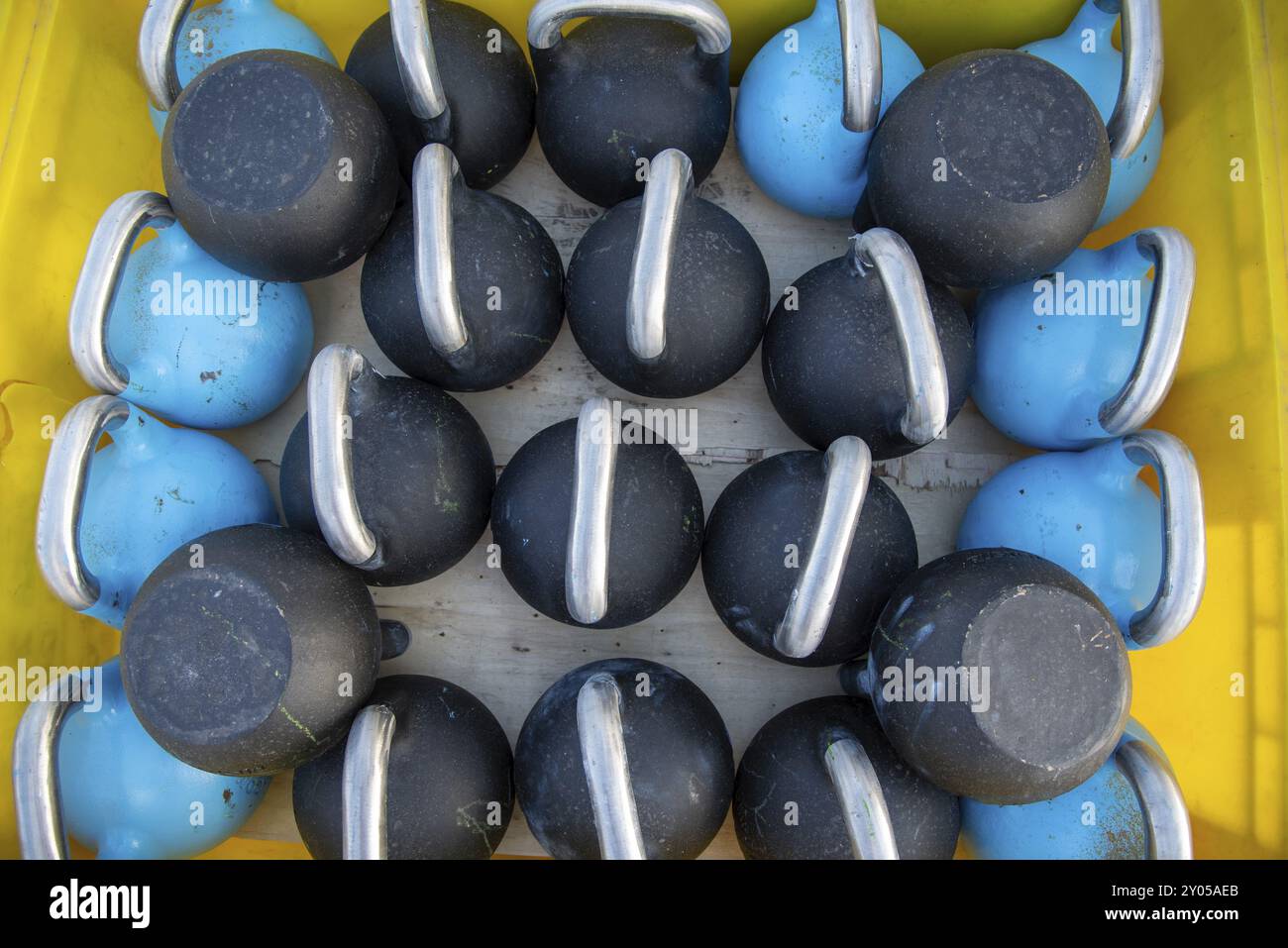 Zenithal view of a collection of yellow kettlebells of varying weights ...