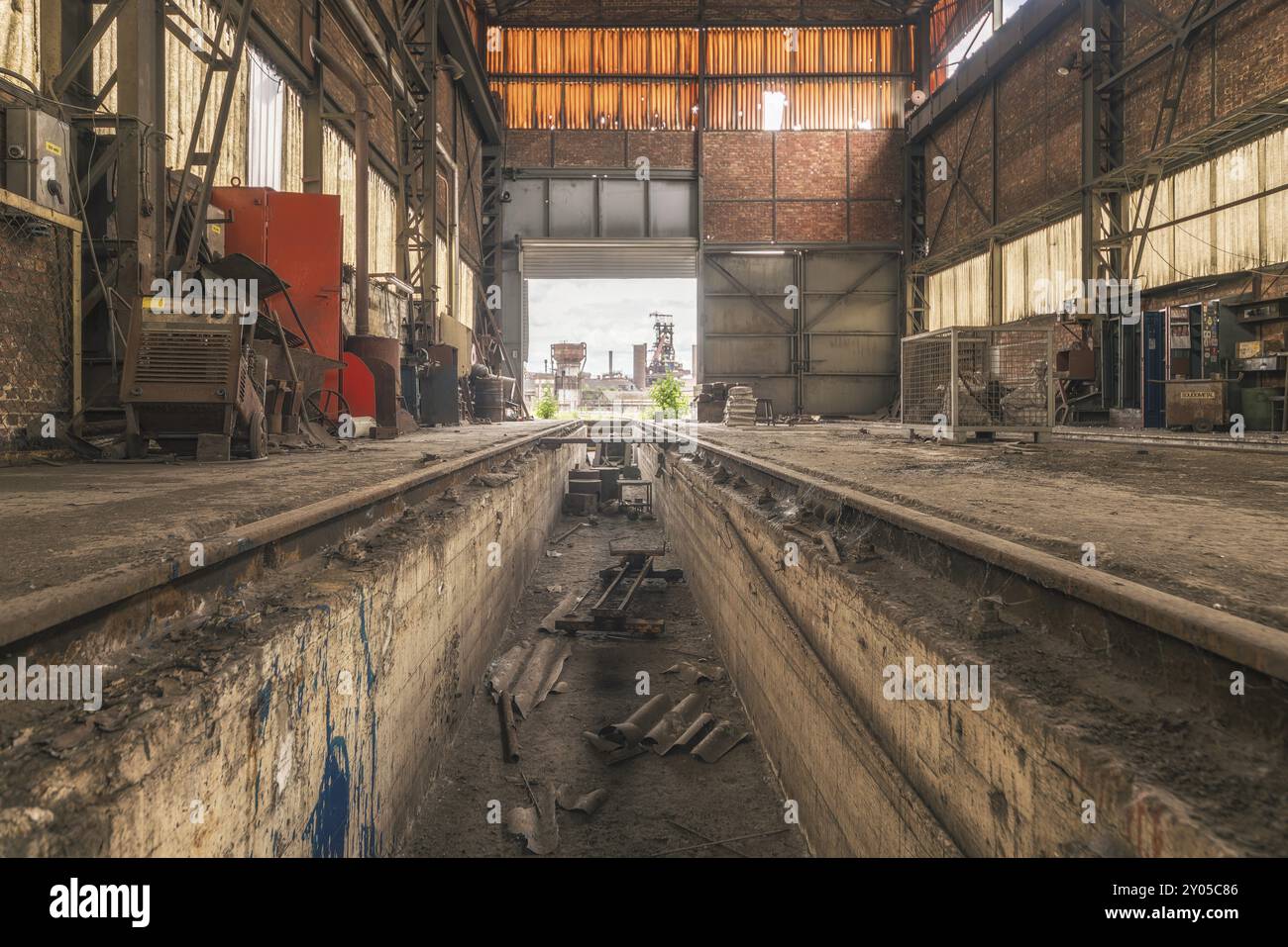 Old abandoned workshop with rails in the centre, numerous tools and ...