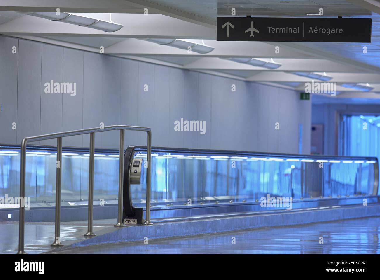 Modern airport terminal with blue illuminated walkway, handrails and ...