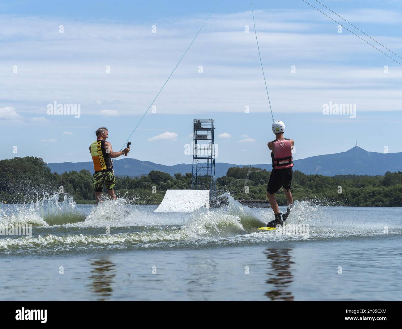 Water sports with wakeboard, two men riding side by side in the lake ...