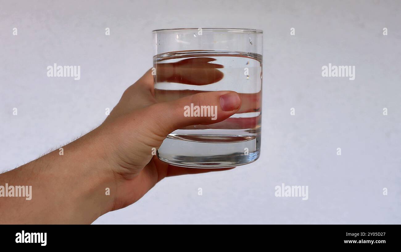 Hand holds a transparent glass with clean water. Crystal clear water in ...