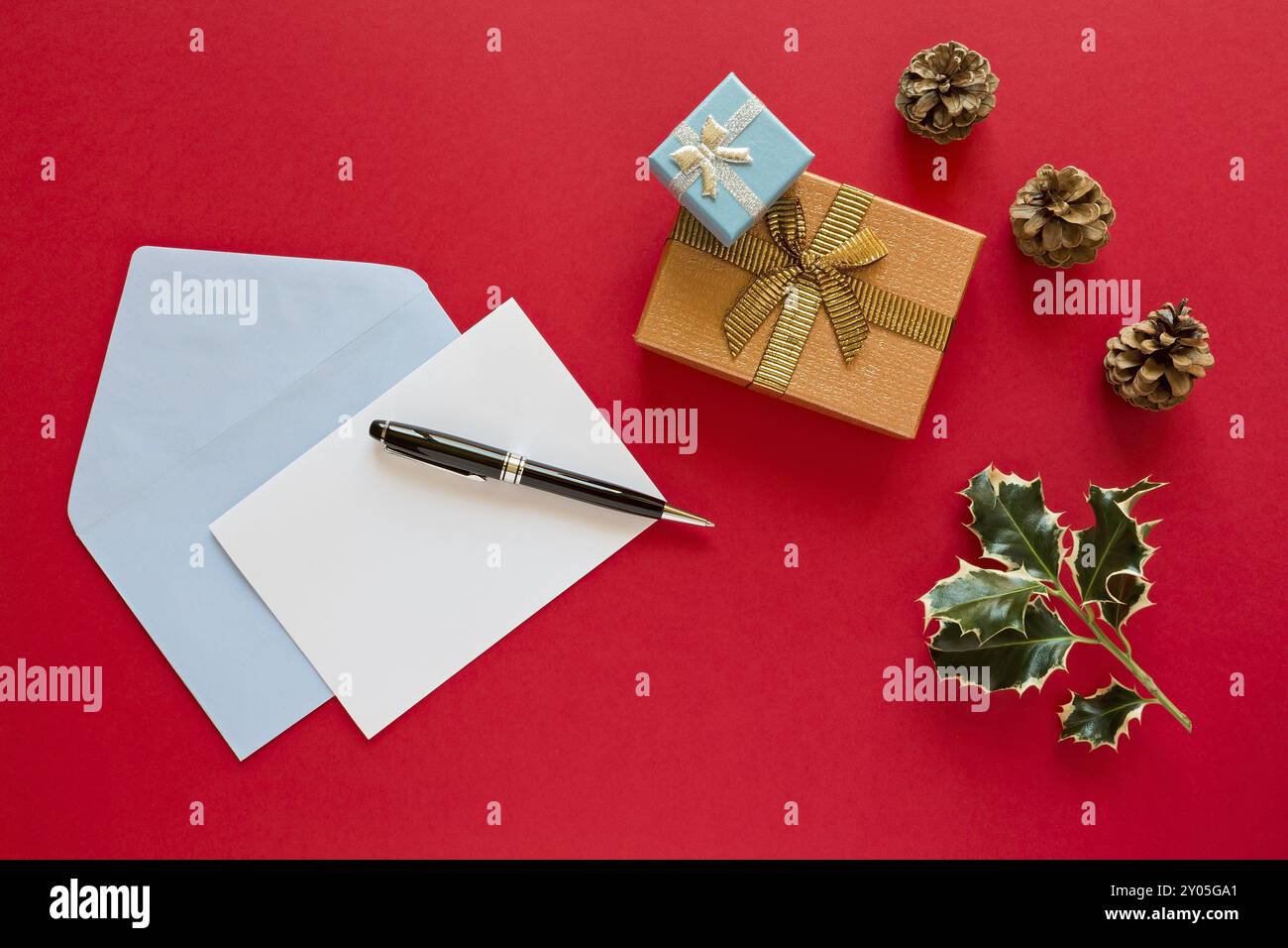 Christmas letter and pen over a red background with presents and pine ...