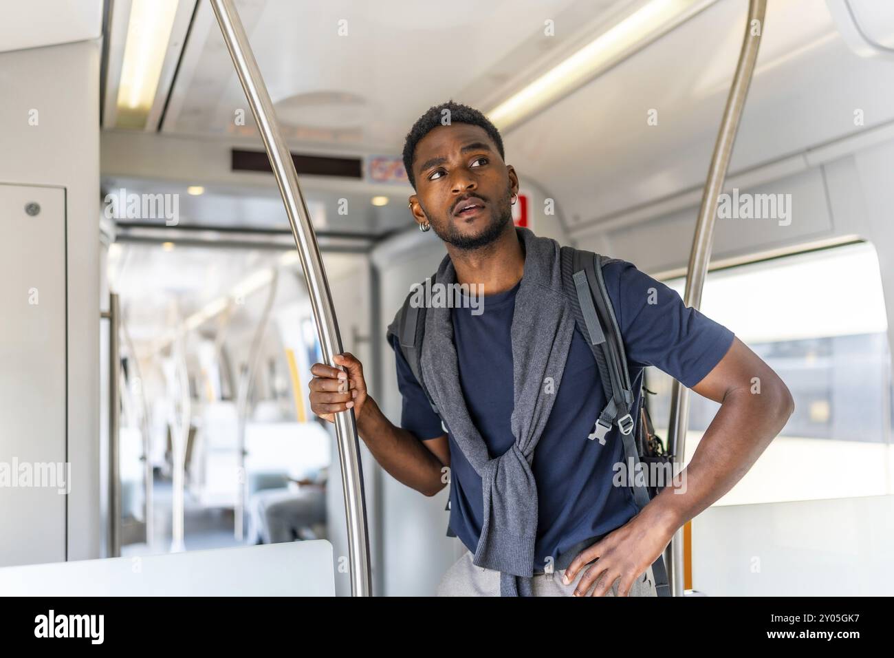 African young man travelling by public transportation standing on an ...