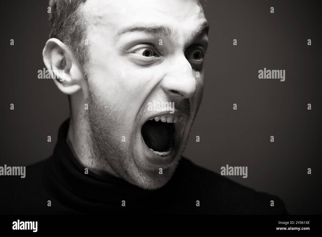 Angry man screaming. A man in a black shirt. Male emotional portrait ...