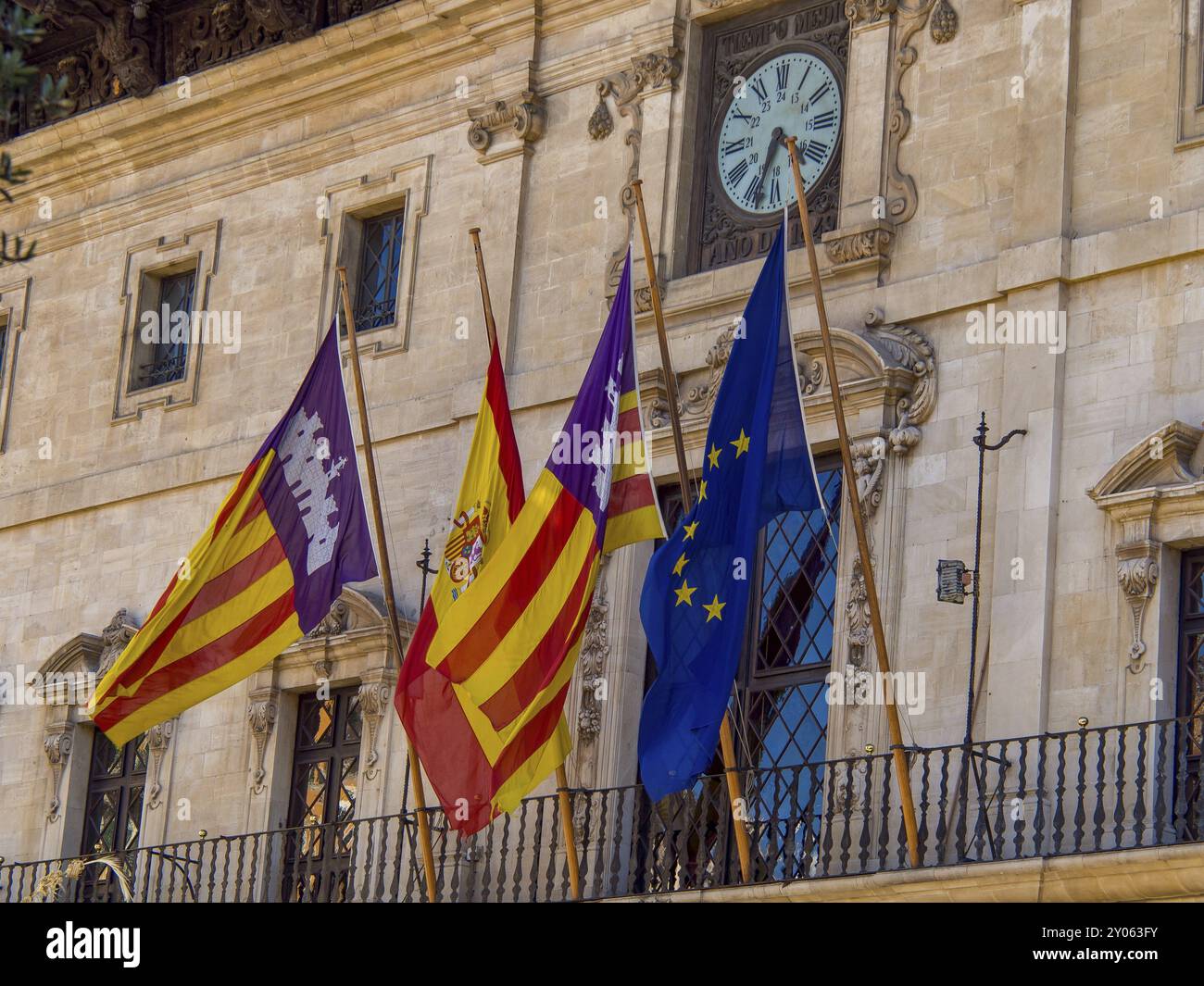 Facade of a historic building with clocks and several flags, dominated ...
