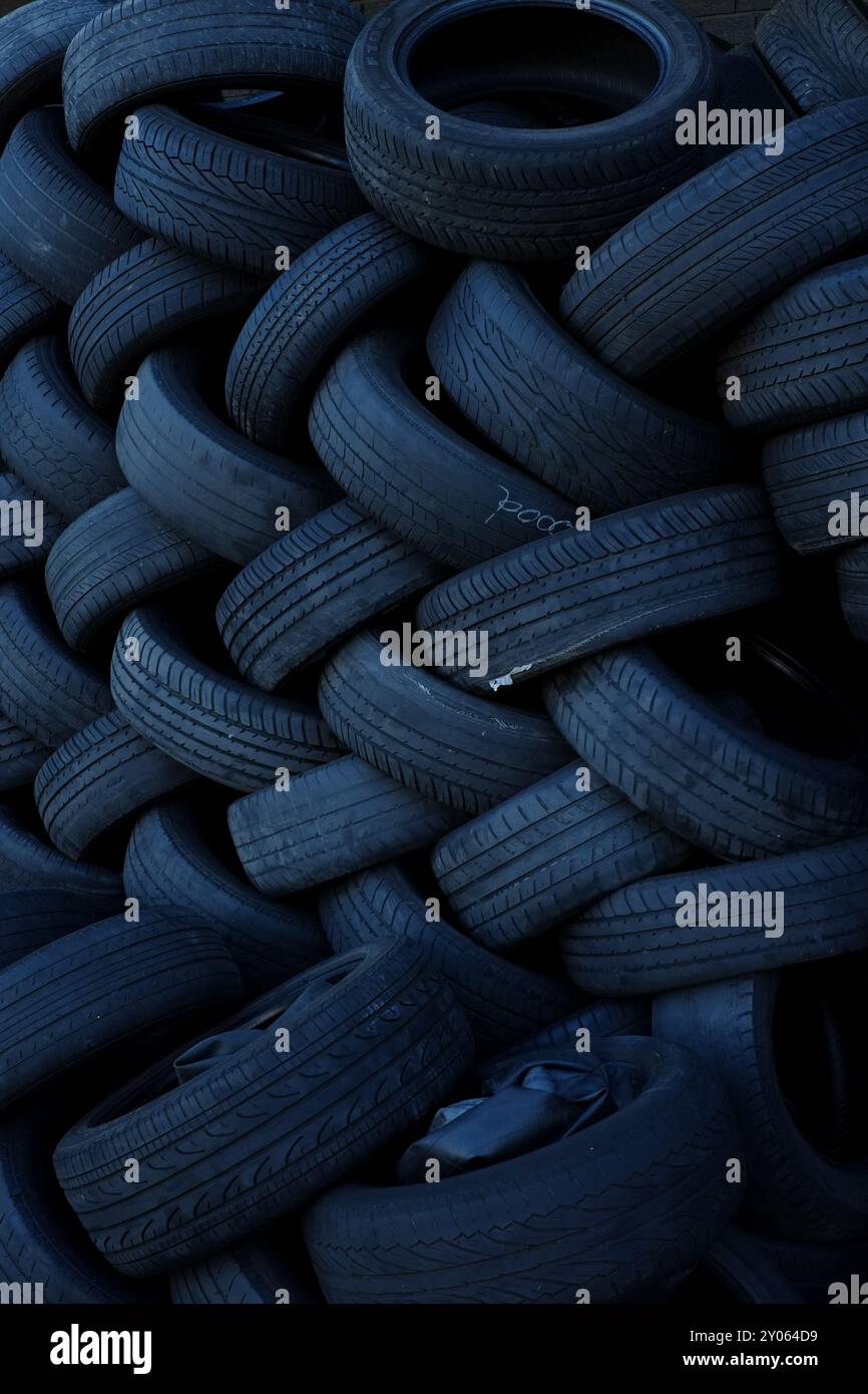 A stack of used car tyres tyres piled up into an interlocking criss ...