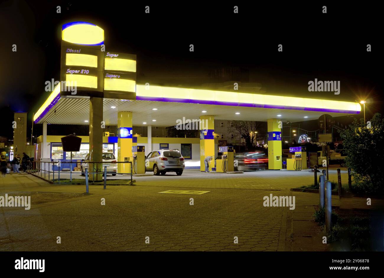 Yellow gas station with cars and people at night Stock Photo - Alamy