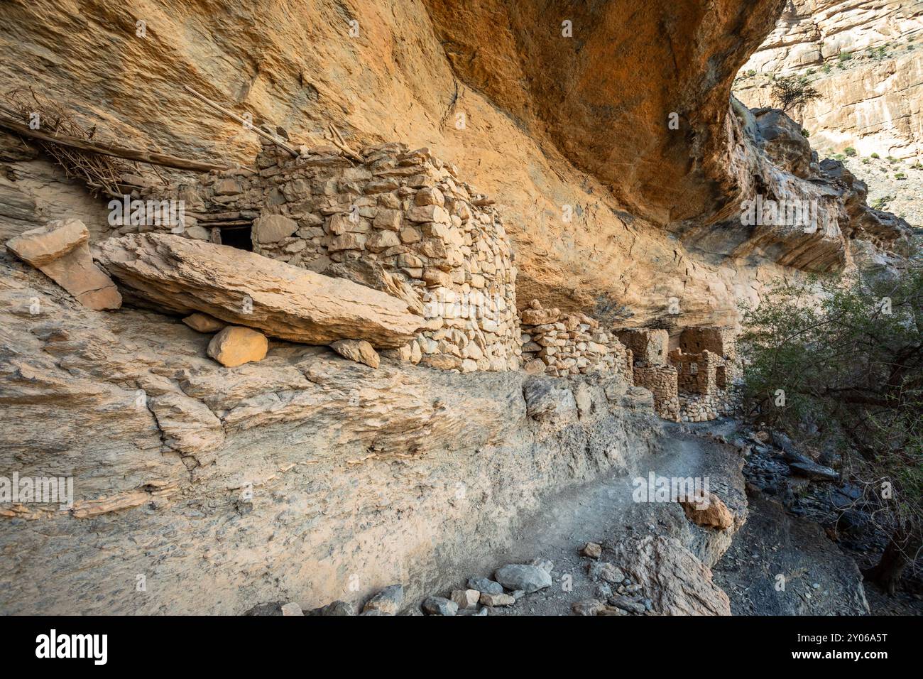 Path along abandoned omani village with stone houses under the canyon ...