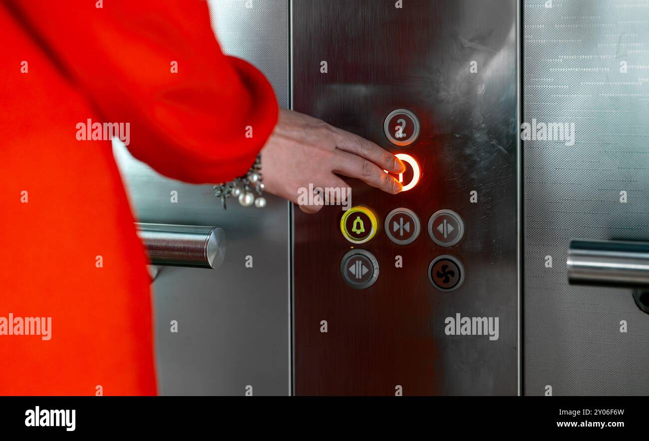Woman in red dress pressing button inside elevator Stock Photo - Alamy