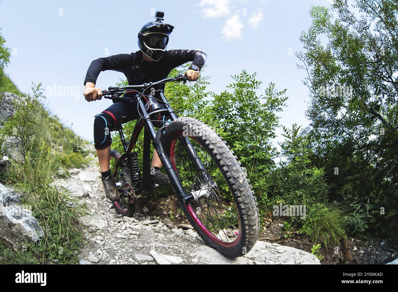 A young rider on a bicycle for downhill descends the rocks in the ...