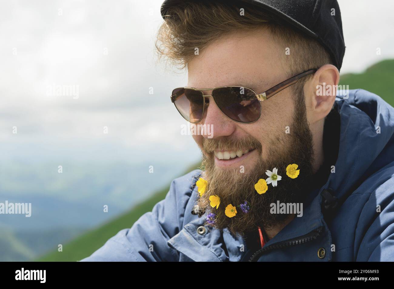 Close-up portrait of a cheerful bearded man in sunglasses and a gray ...