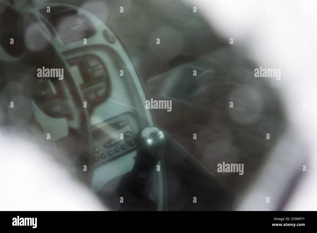View through a frozen side window into the interior of a car. Steering ...