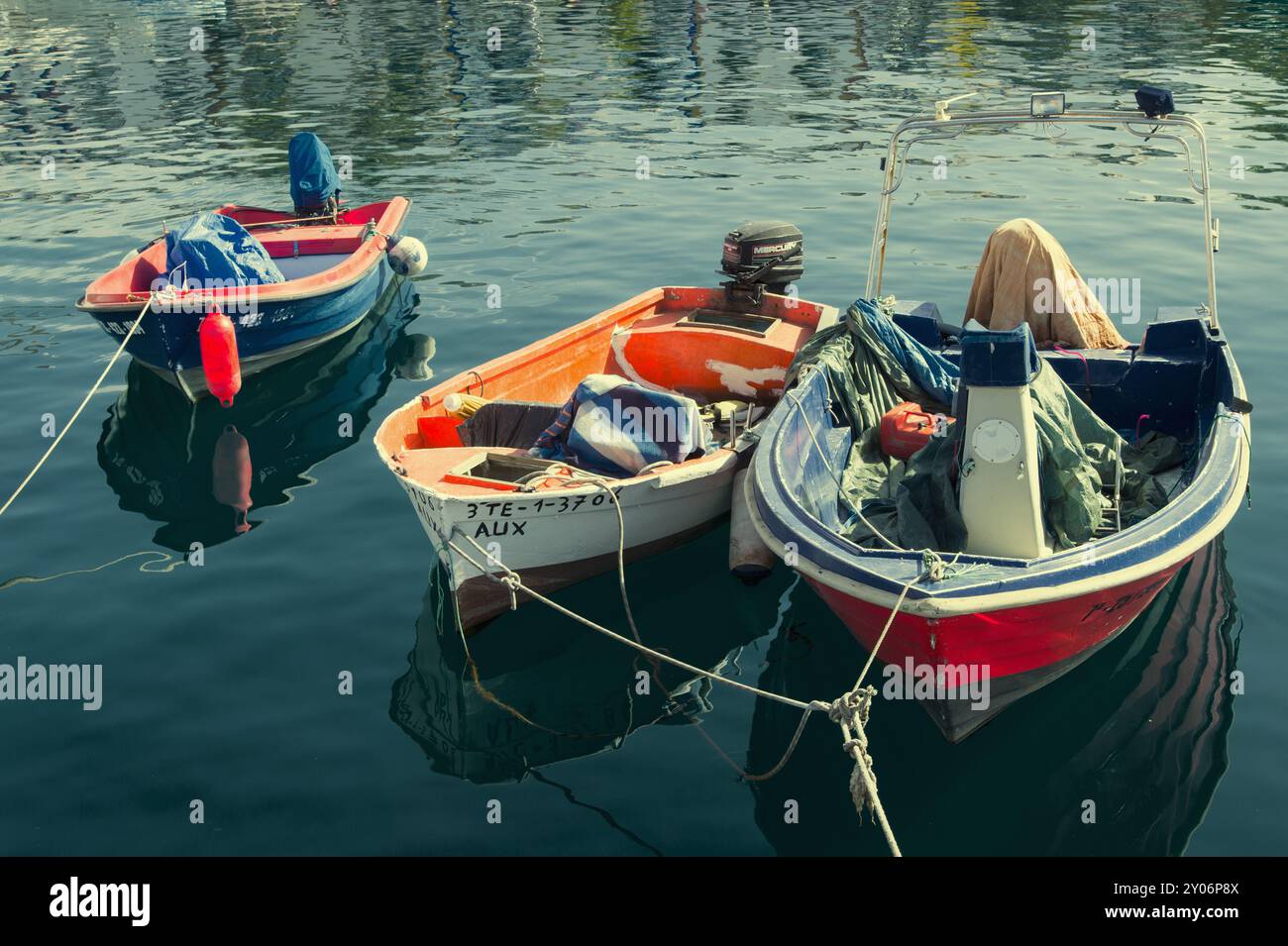 3 colourful fishing boats moored side by side in the harbour basin of ...