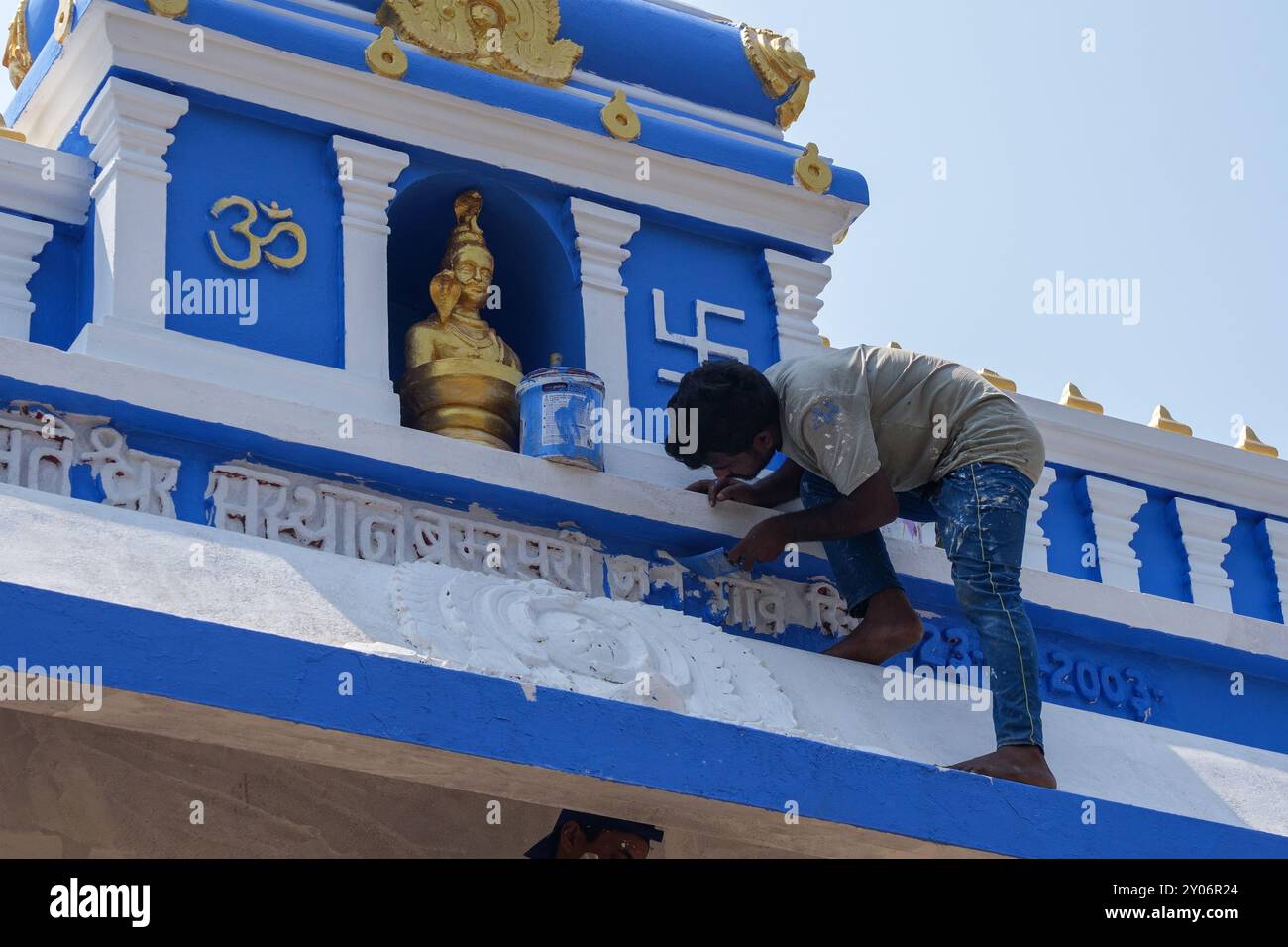 GOA, India - February 27, 2024: A man paints a wall in a temple. Sacred ...