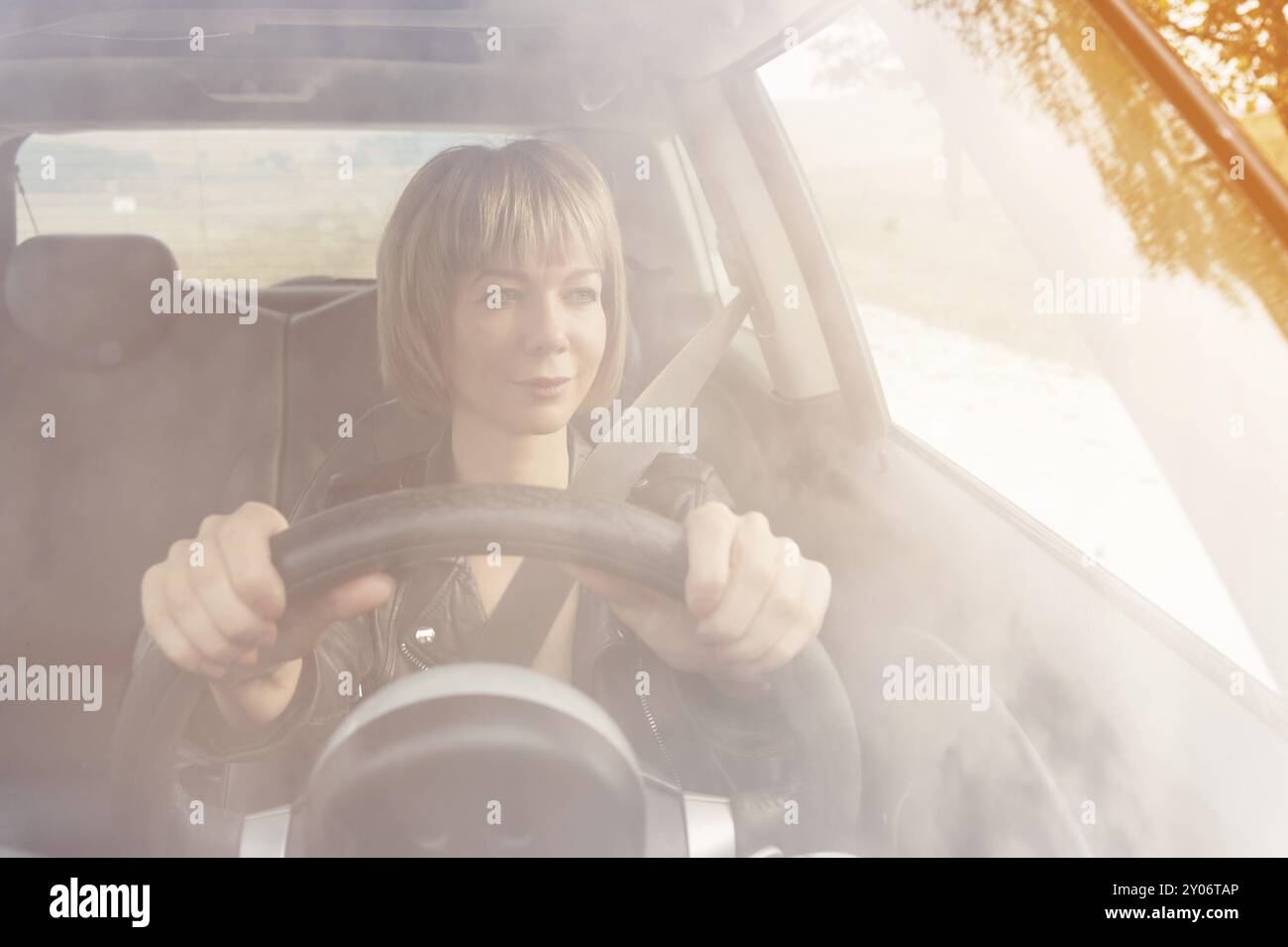 A cute young woman with a short haircut sits behind the wheel of a ...