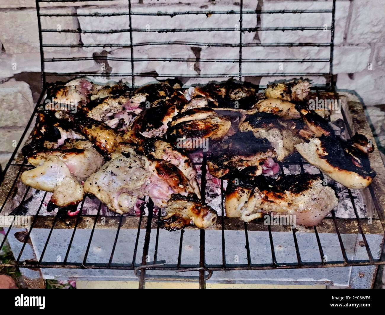 chicken quarters on a grid grilled and barbecued on charcoal flames ...