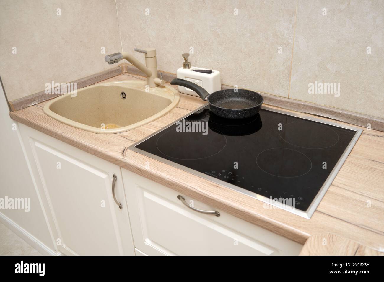 Kitchen countertop with beige sink, faucet, soap dispenser, and black ...