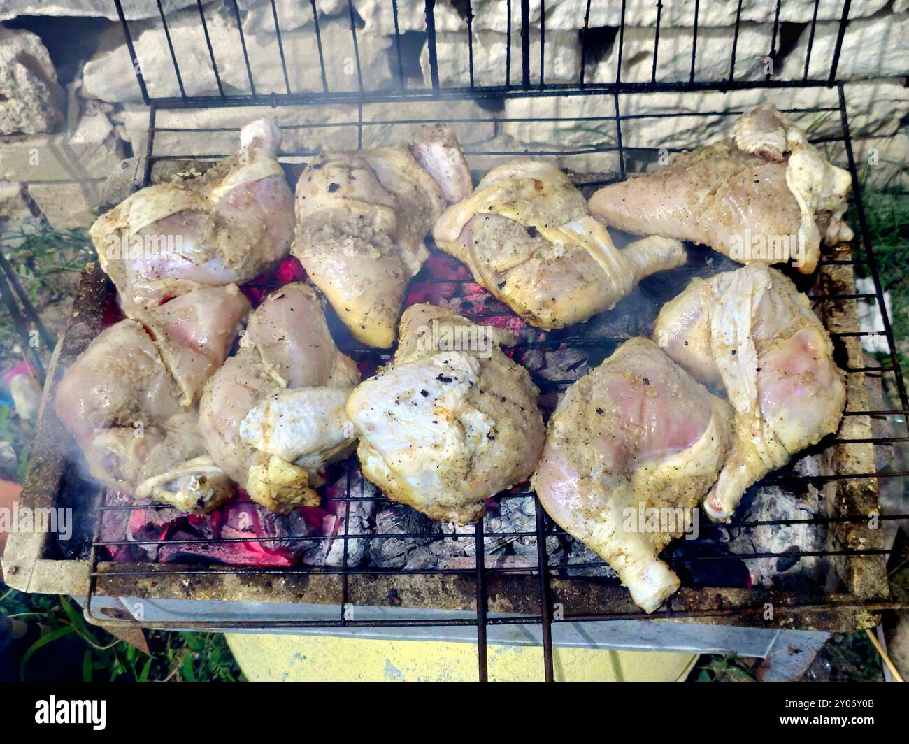 chicken quarters on a grid grilled and barbecued on charcoal flames ...