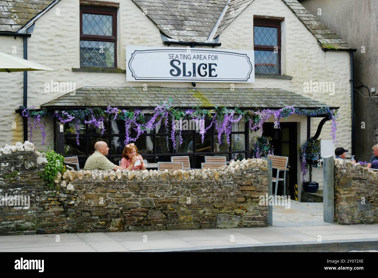 Holiday makers eating and drinking outside the Slice Cafe, Tintagel ...