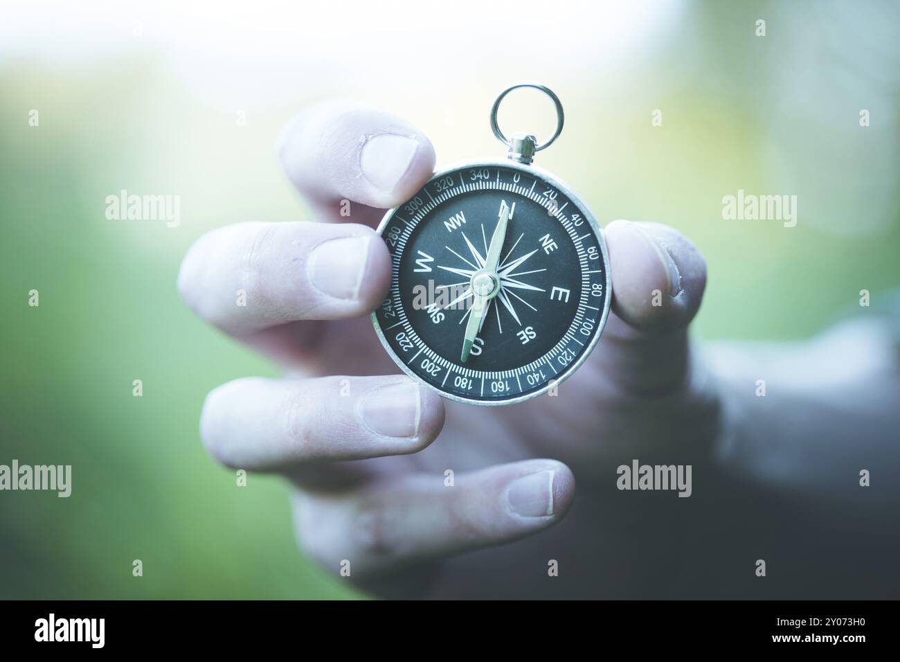Young man on an adventure is holding a compass in his hand for finding ...