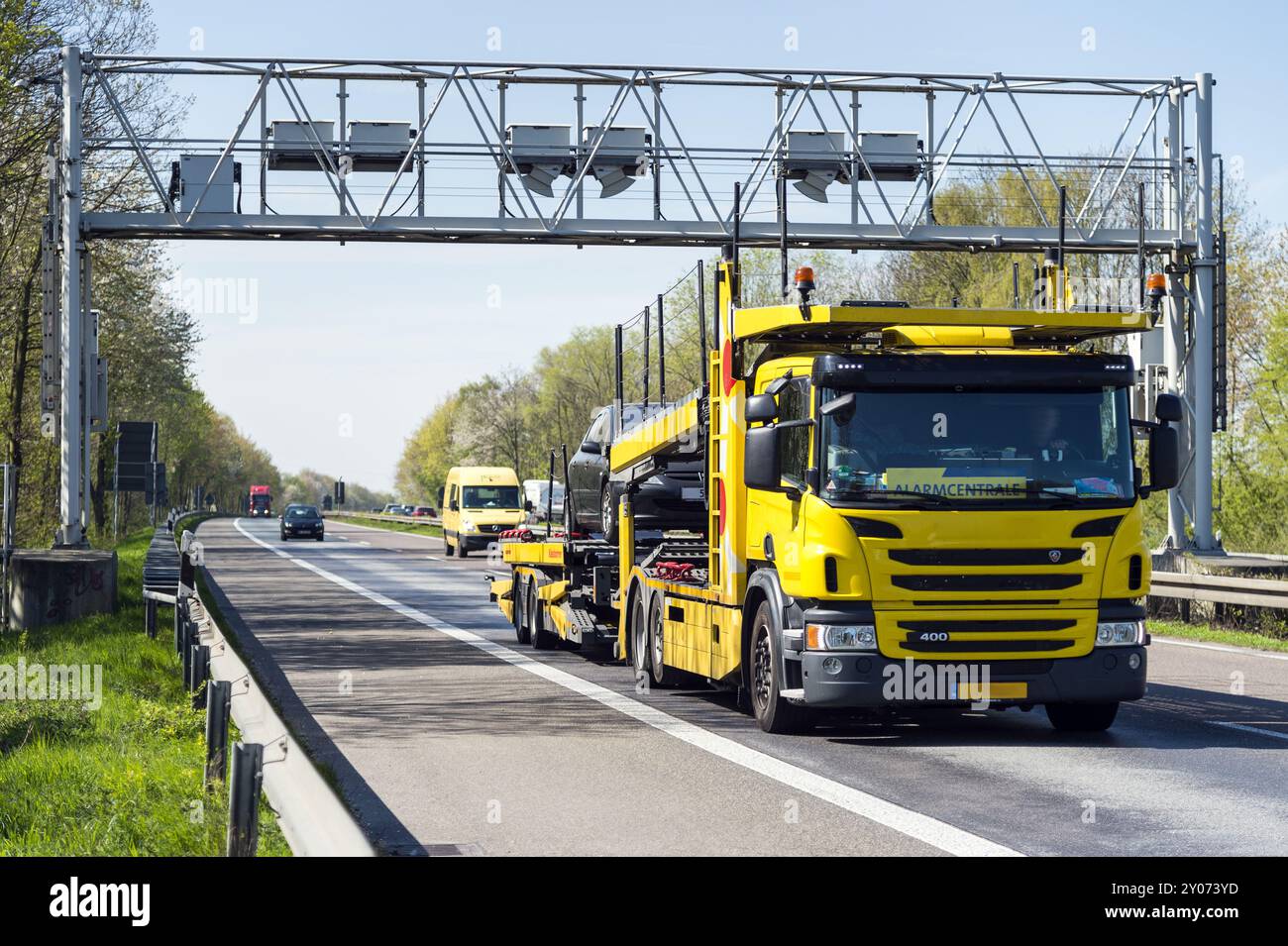Yellow breakdown recovery vehicle on the motorway under a toll bridge ...