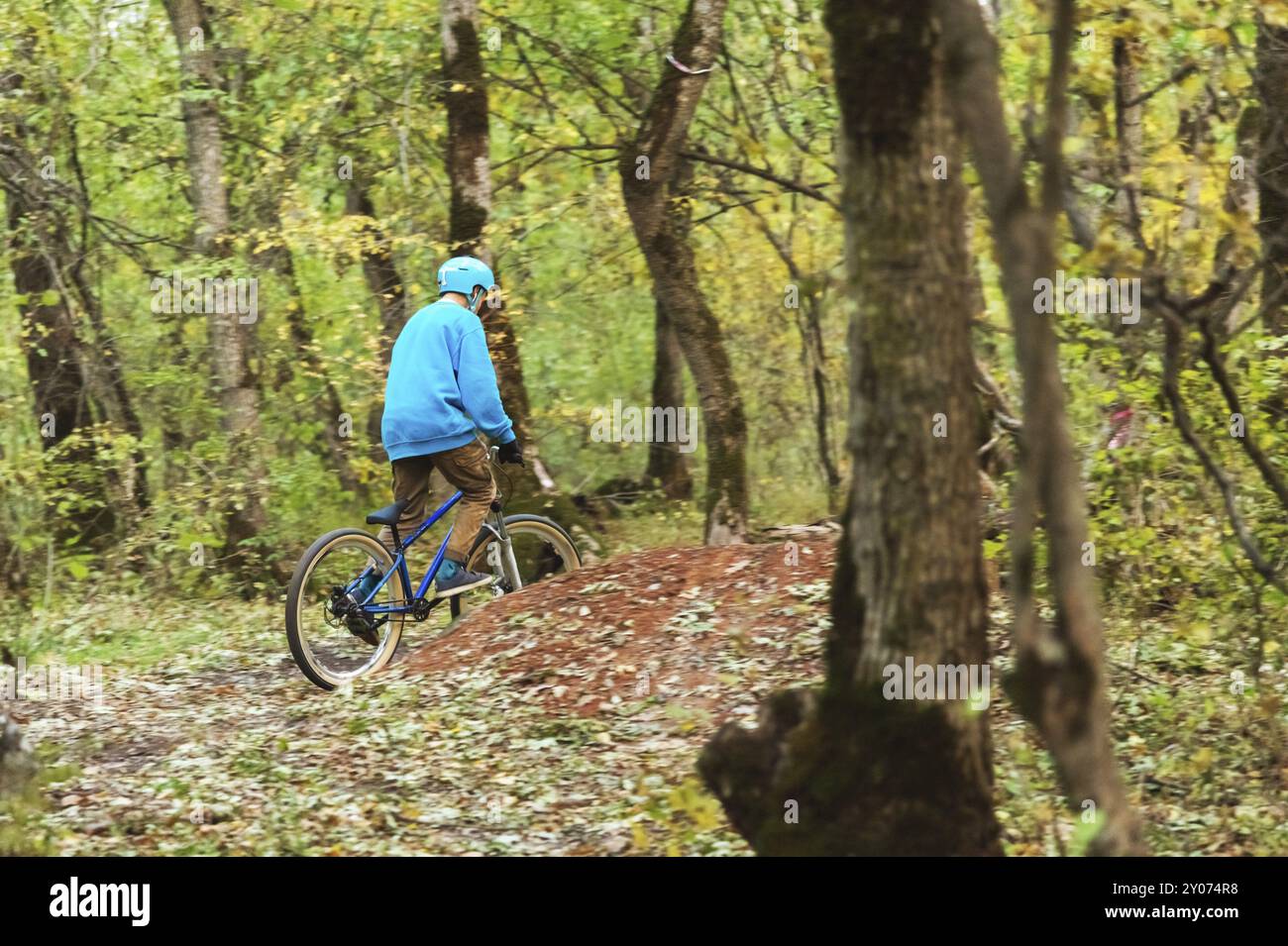 A young rider driving a mountain bike rides at speed downhill in the ...