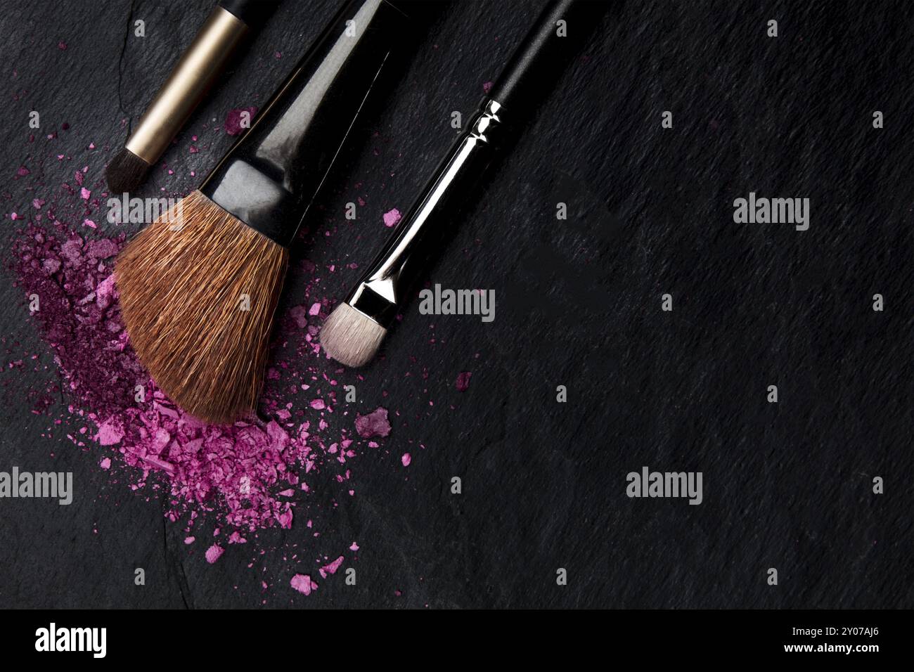 Make-up brushes with crushed cosmetics, shot from above on a black ...