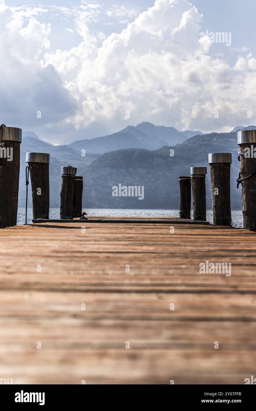 Wooden dock pier, blue lake, mountains and sky with clouds at lago di ...