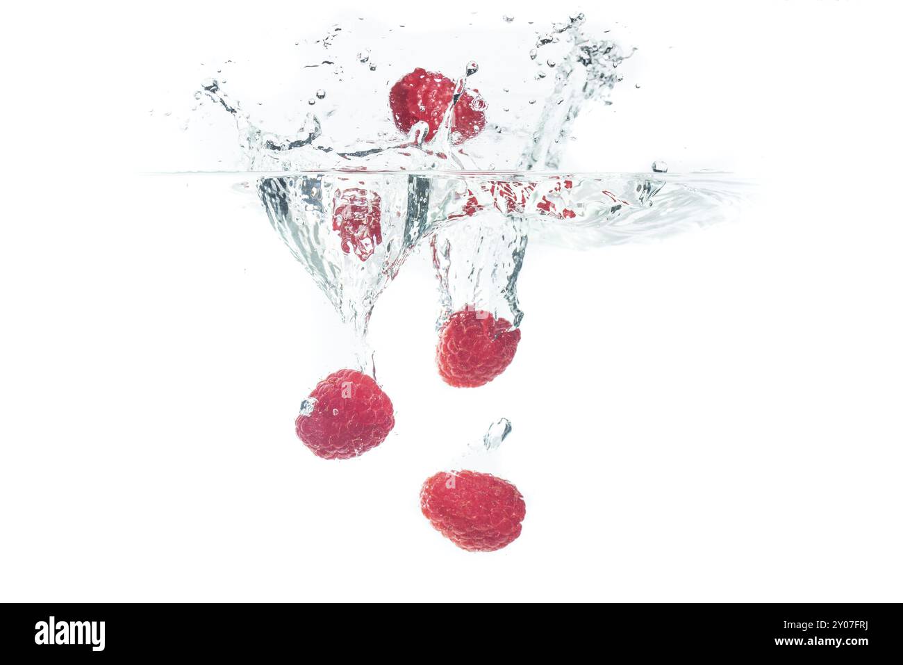 Bunch of juicy delicious looking raspberries splashing into water ...