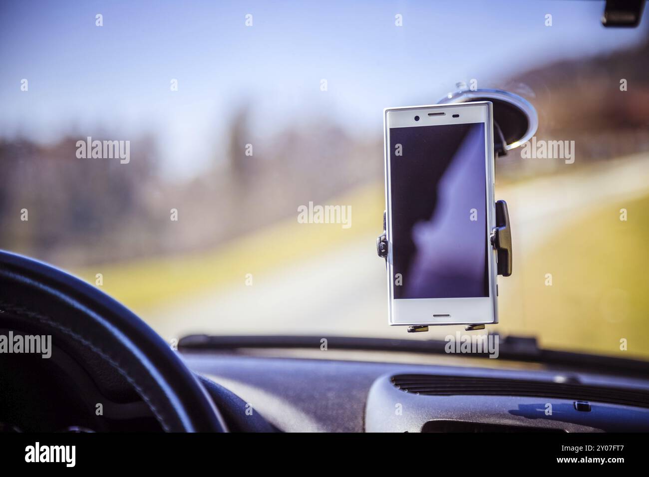 Interior of a modern car on a sunny day. Smartphone on mobile mount, used as navigation device ...