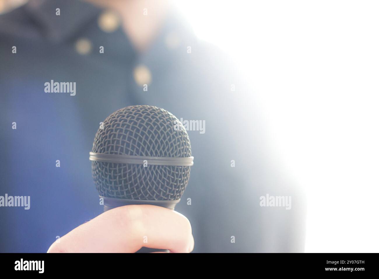 Interview: Black microphone in the foreground, man with blue shirt in ...
